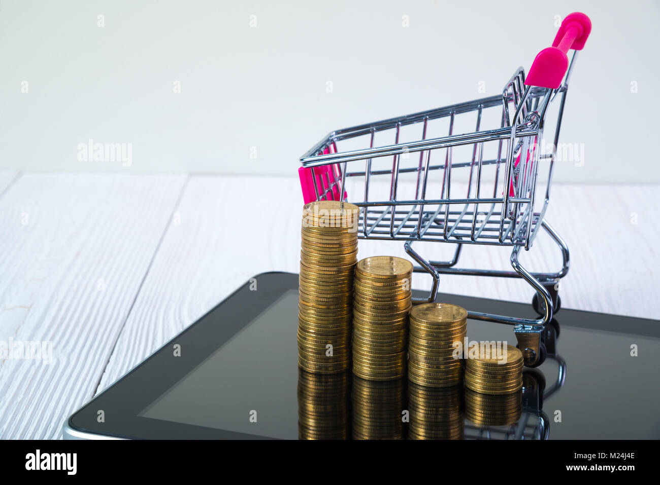 Step of coin stack and shopping cart or supermarket trolley on tablet ...