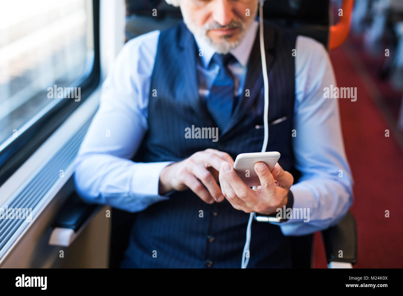 Mature businessman with smartphone travelling by train Stock Photo - Alamy