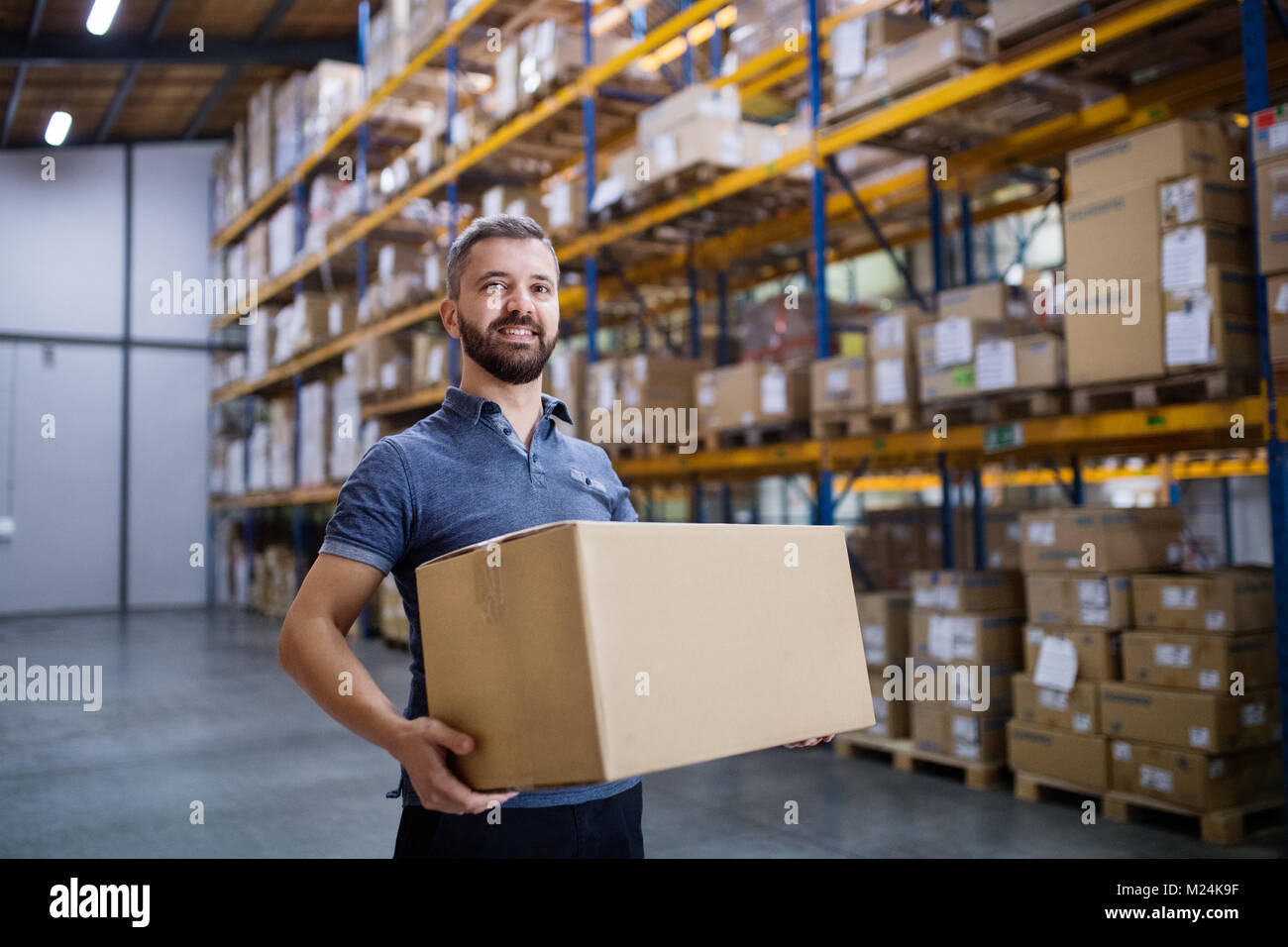 Male warehouse worker with a large box Stock Photo - Alamy