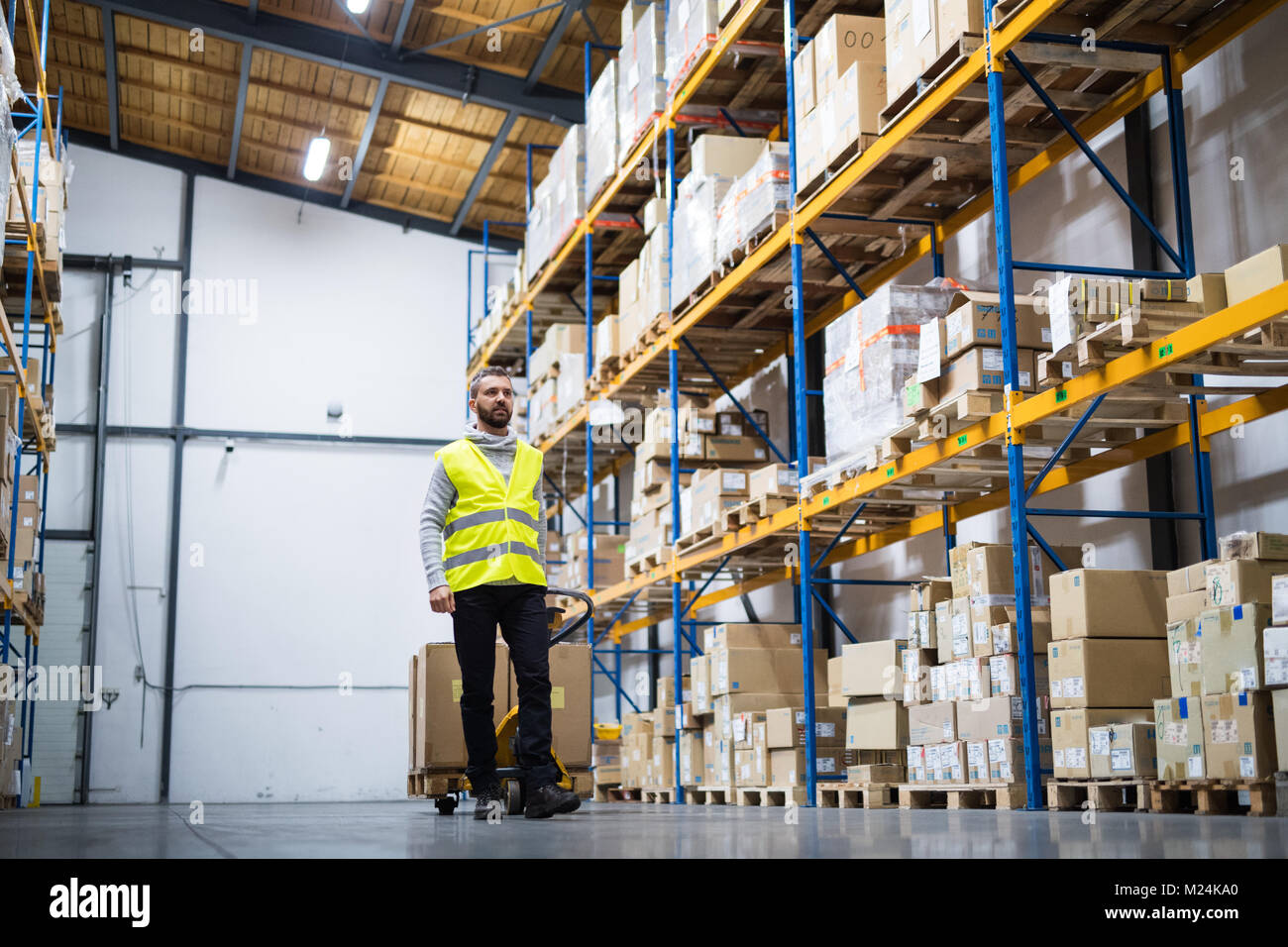Male warehouse worker pulling a pallet truck Stock Photo - Alamy