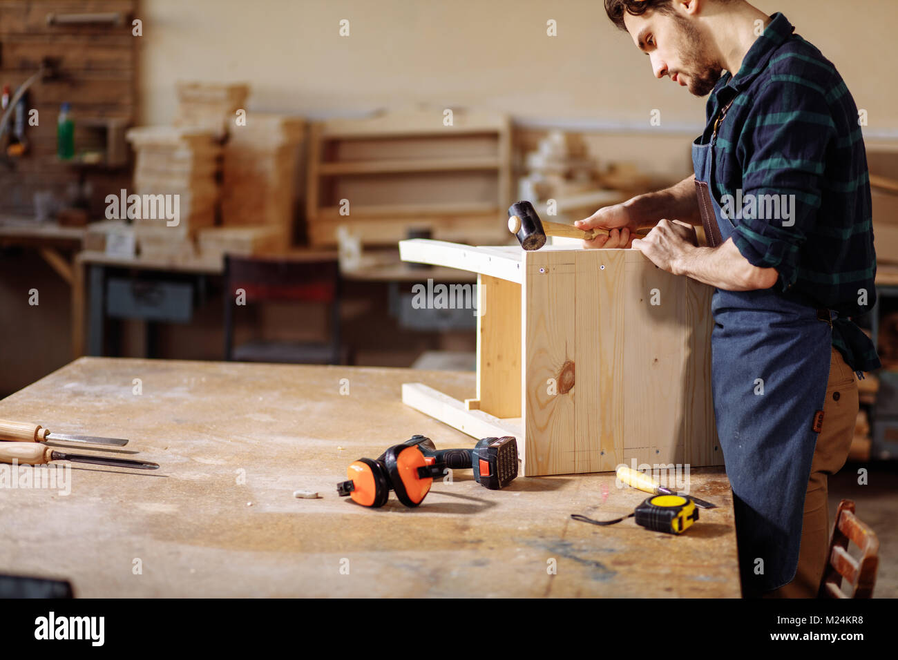 carpenter hammering a nail into wooden board Stock Photo - Alamy