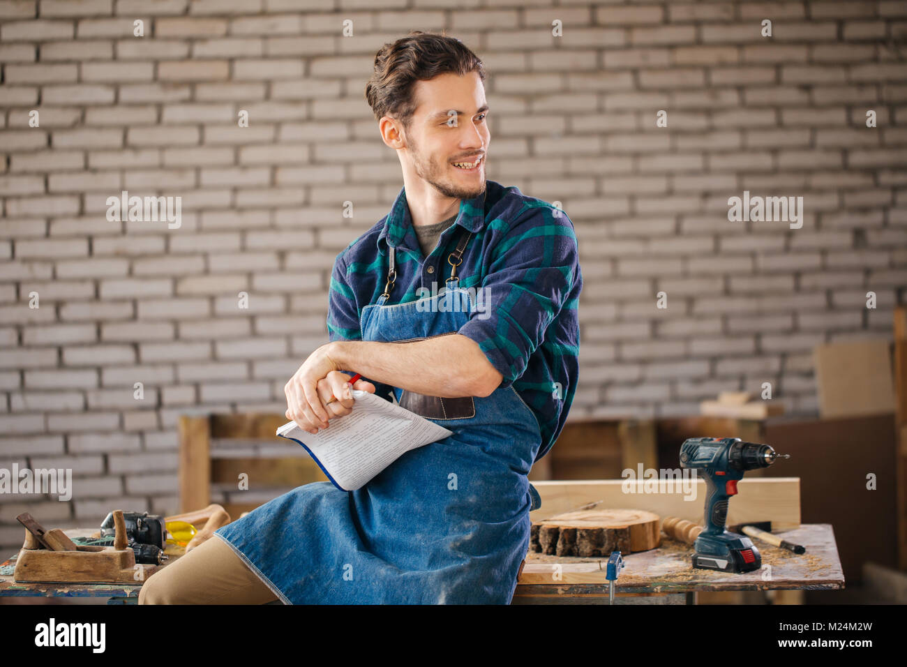 Man carpenter in his home studio draws sketches in pencil in notebook ...