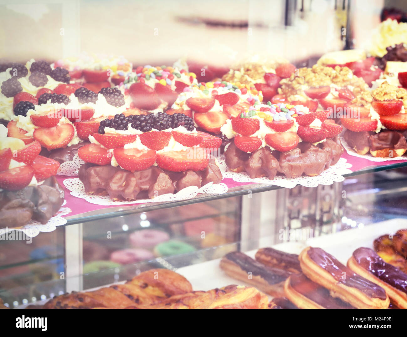 Sweet food behind a bakery shop window. Eclairs, baked goods and fruits ...