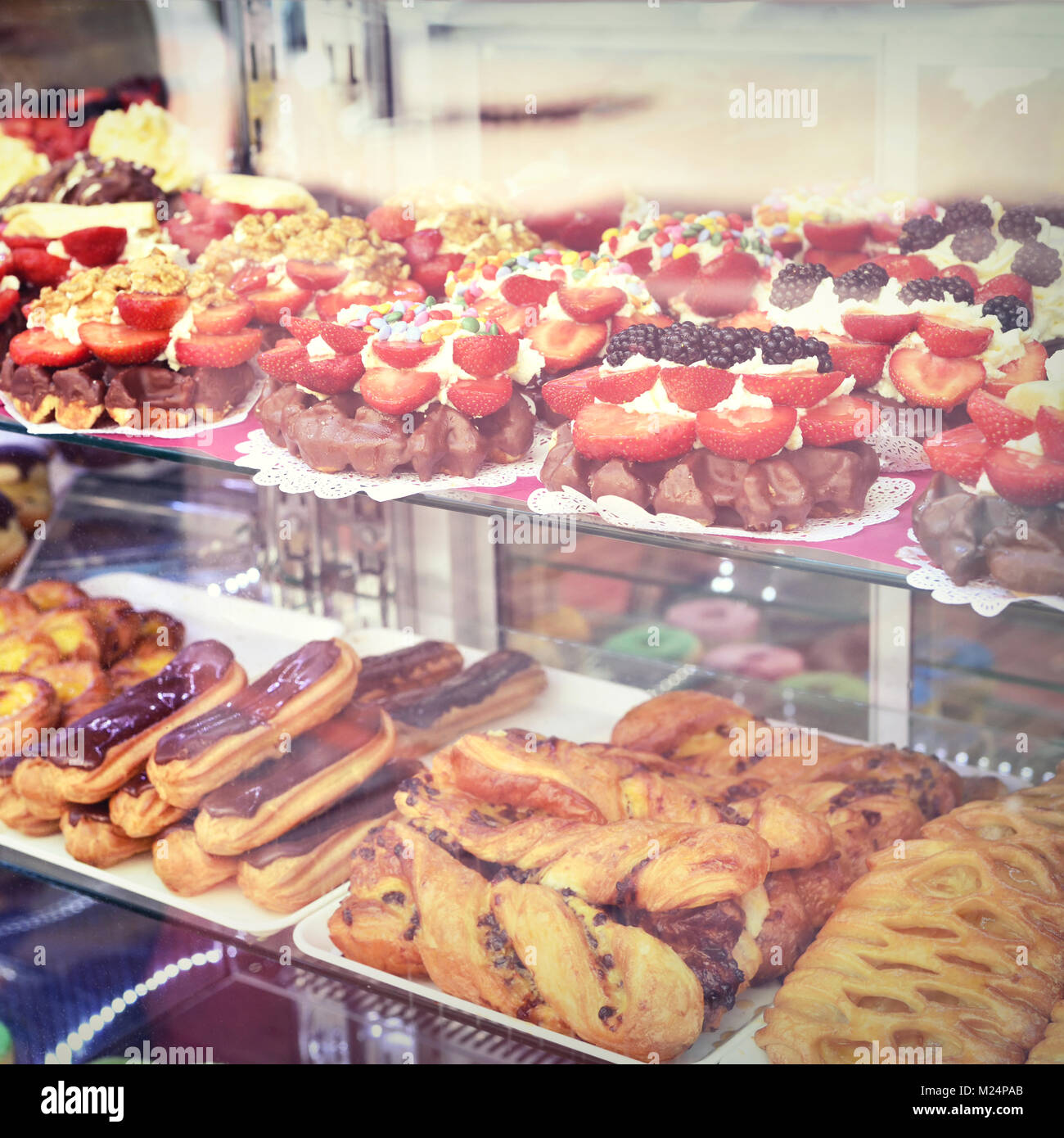 Sweet food behind a bakery shop window. Eclairs, baked goods and fruits ...