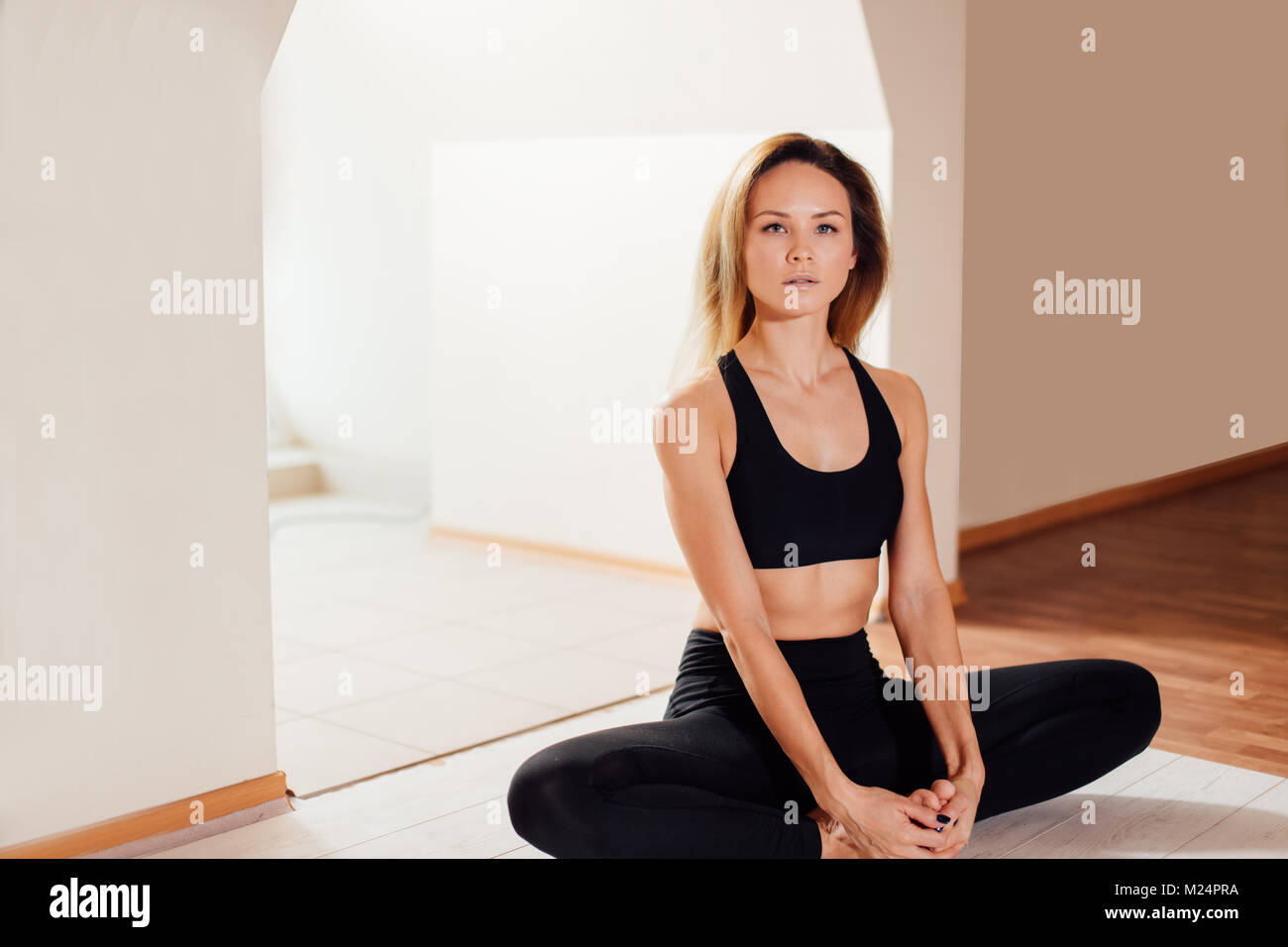 woman doing yoga exercise, sitting in baddha konasana, butterfly pose ...