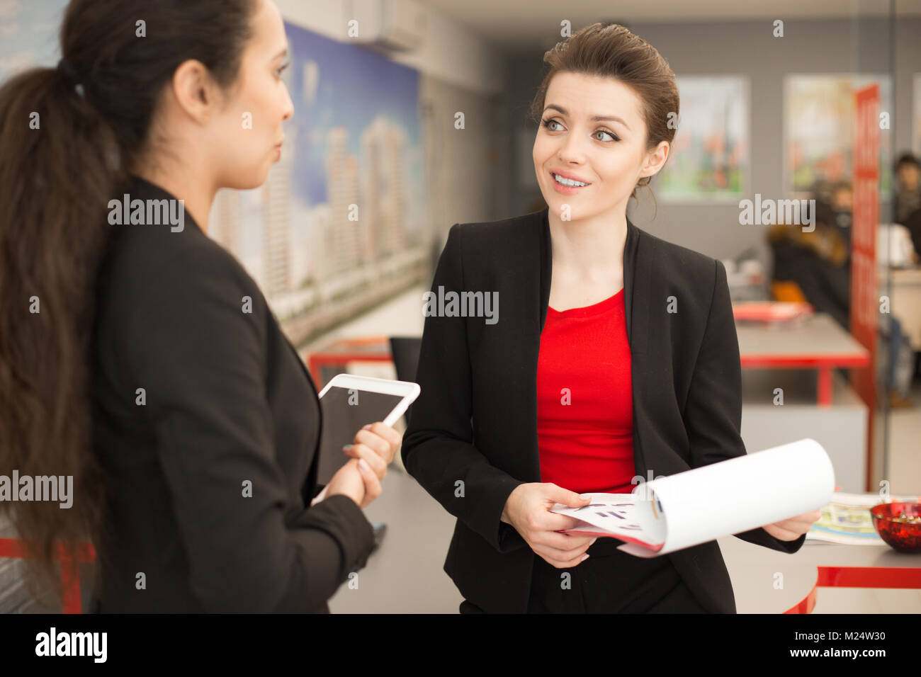 Portrait of two business women wearing black and red uniform standing ...