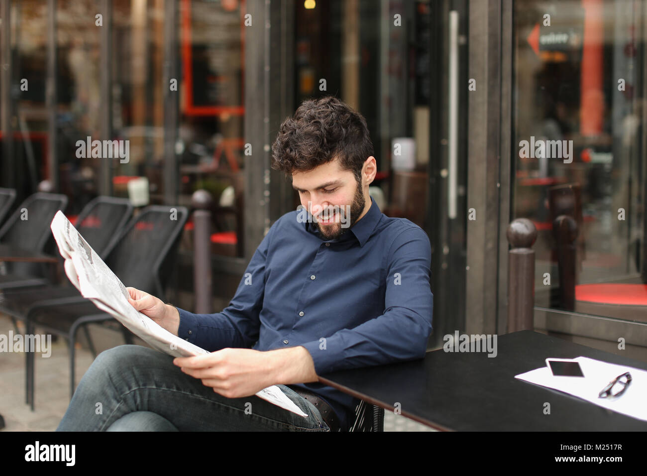 Journalist with close up face reading newspaper article at cafe Stock ...