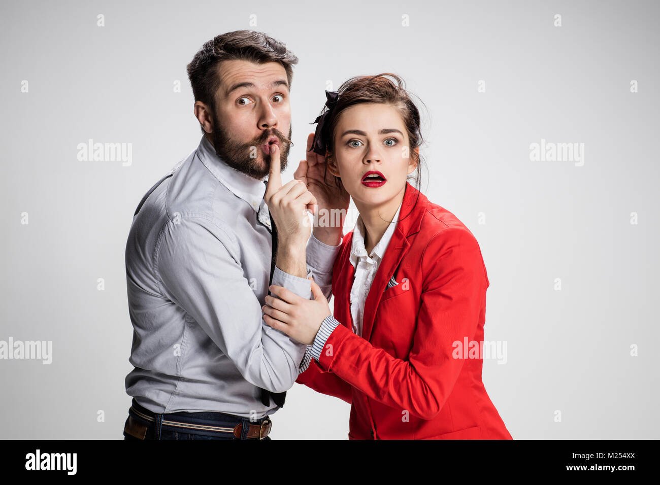 Young man telling gossips to his woman colleague at the office Stock ...