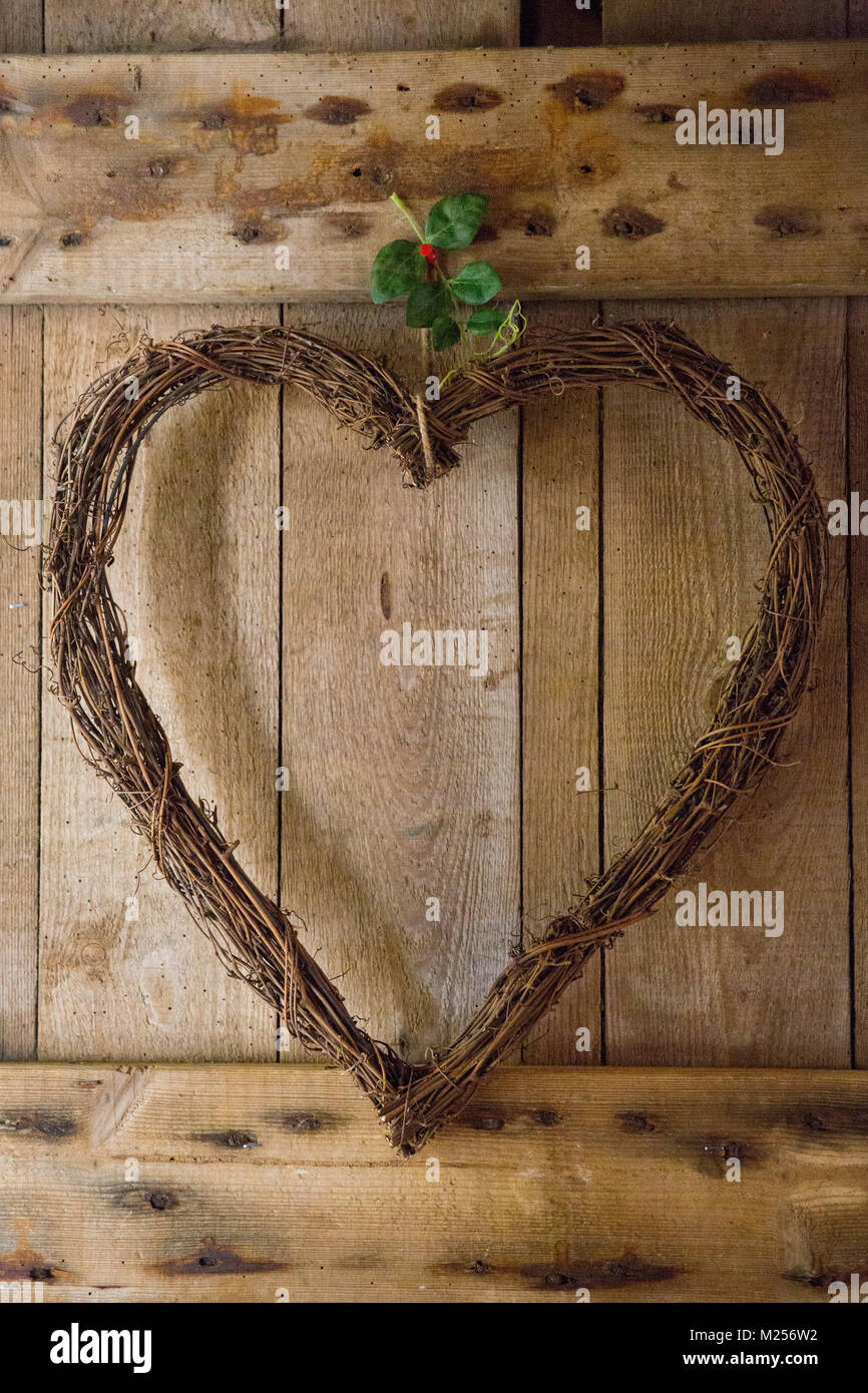 Wicker heart shaped decoration hanging on barn door Stock Photo - Alamy