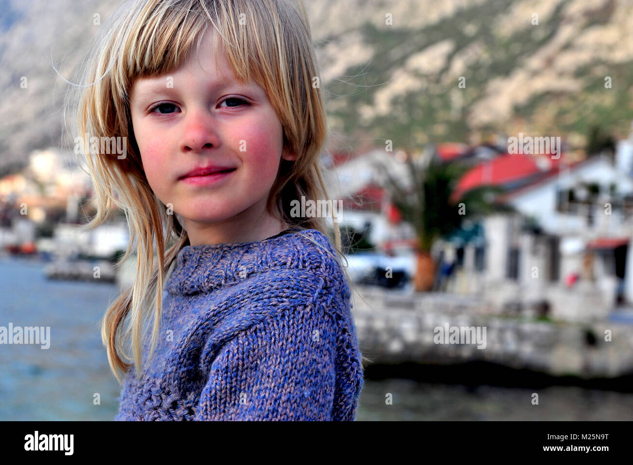 Portrait of a boy with long hair with mediterranean village on ...