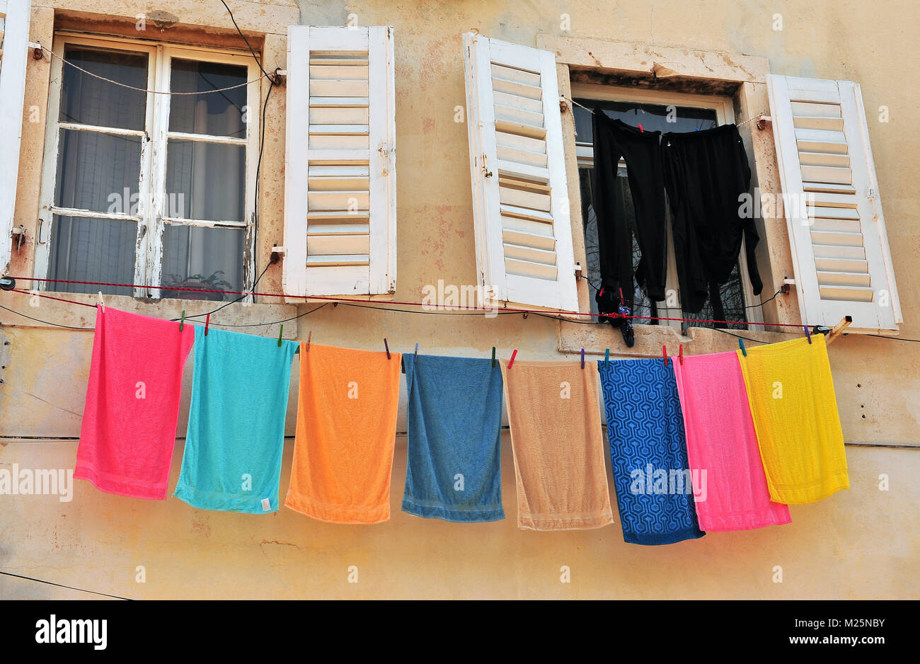 Two open windows with hanging colorful towels Stock Photo - Alamy