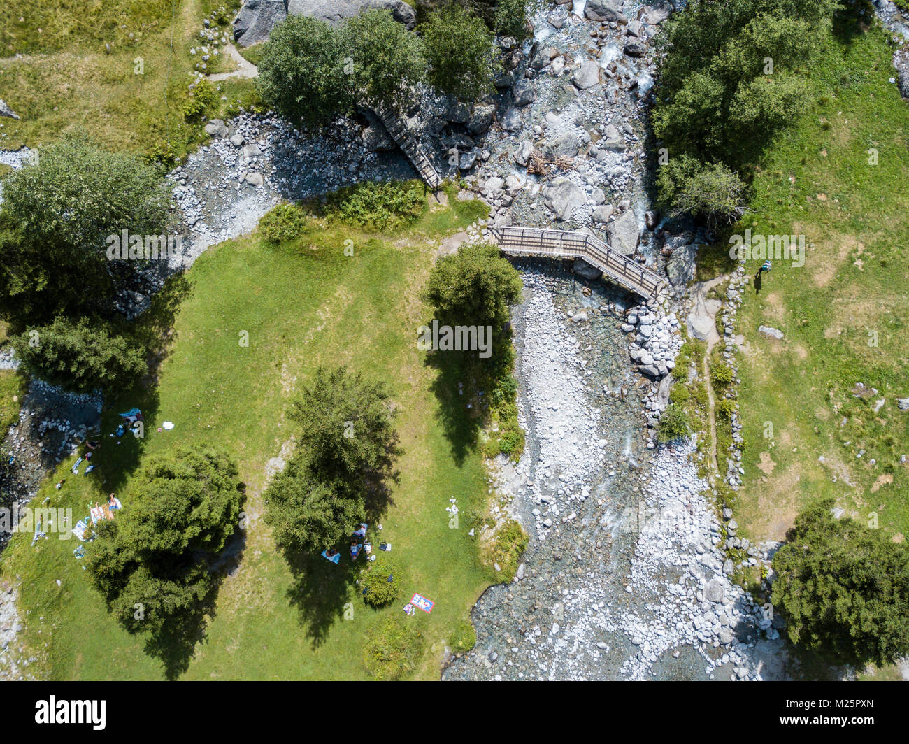 Aerial view of a wood bridge and a river in Val di Mello, a green ...