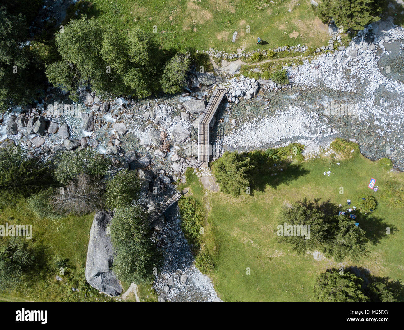 Aerial view of a wood bridge and a river in Val di Mello, a green ...