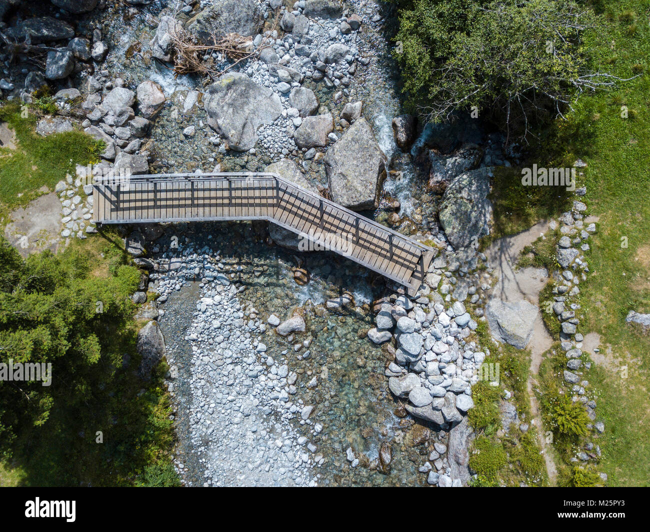 Aerial view of a wood bridge and a river in Val di Mello, a green ...