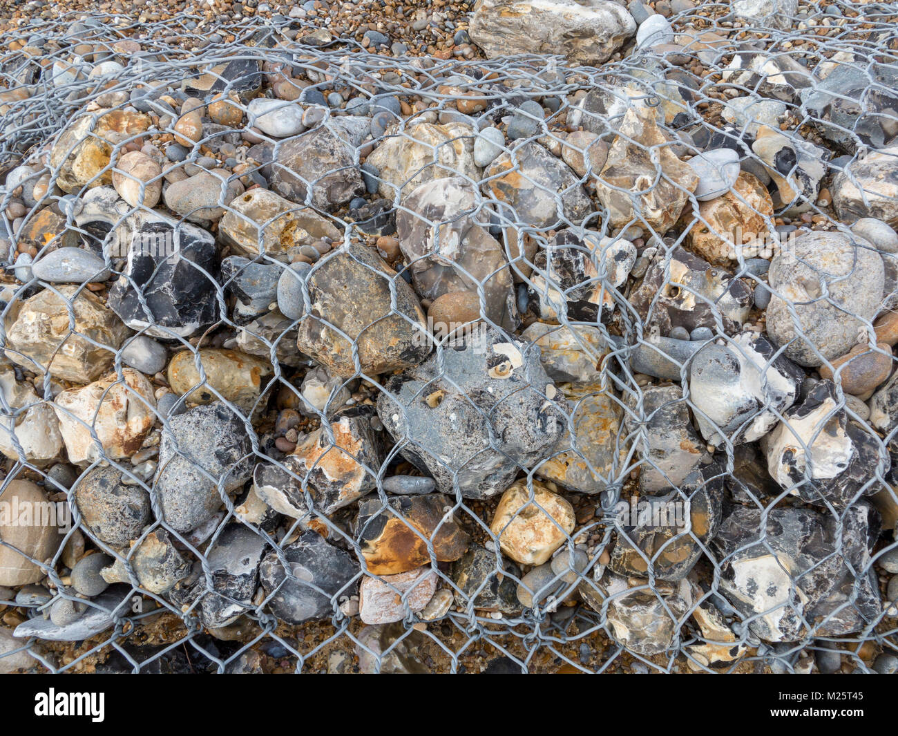Sea defences made from wire mesh cages containing large beach pebbles ...