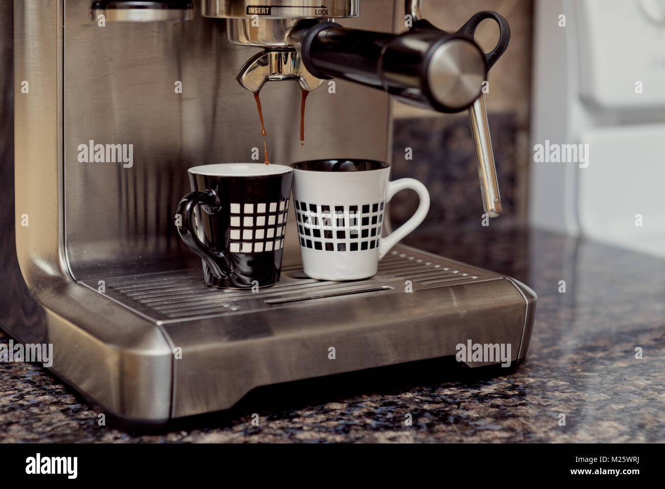Home espresso machine on kitchen countertop making two cups coffee ...