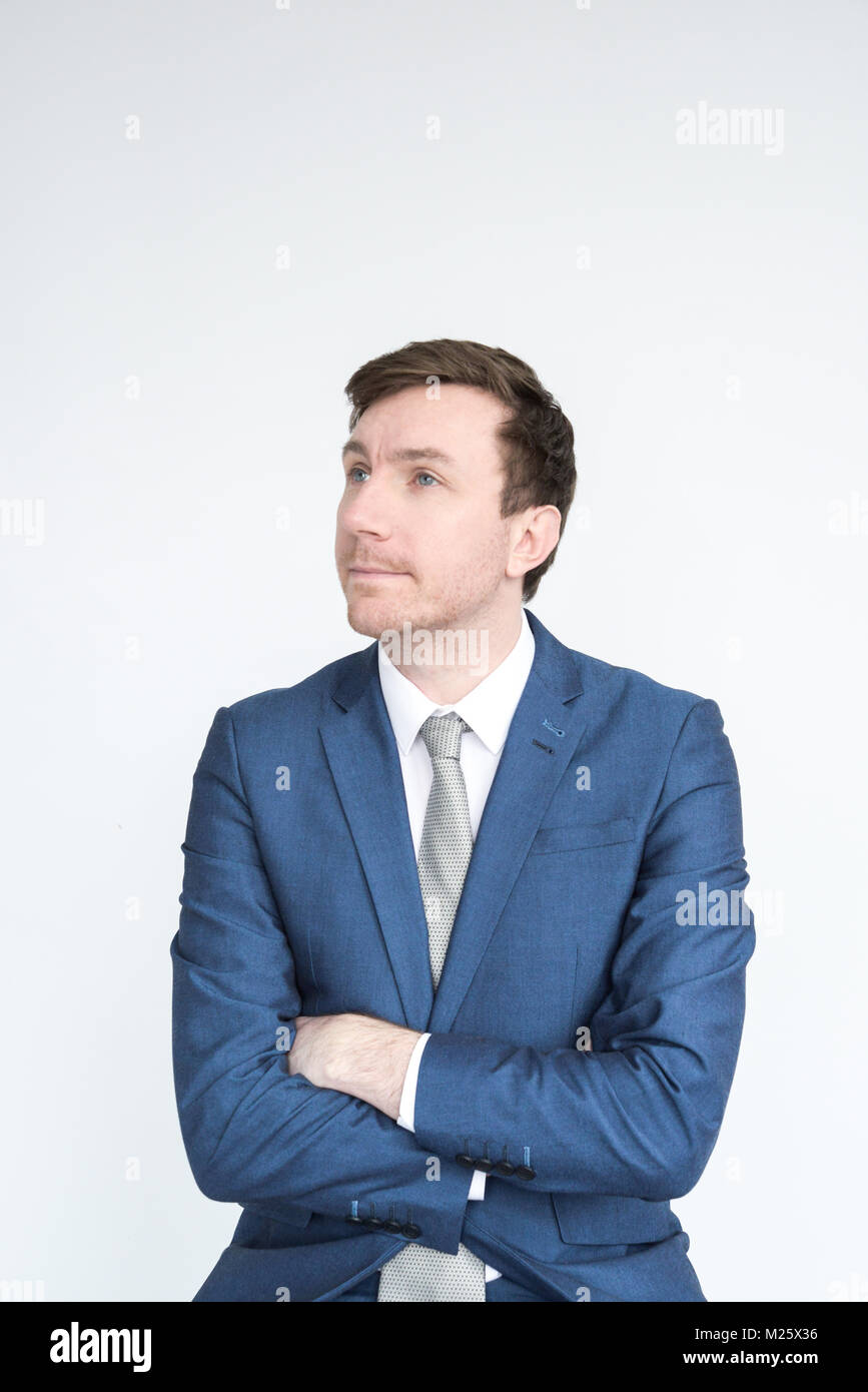 portrait of smartly dressed white male arms folded looking up and to ...