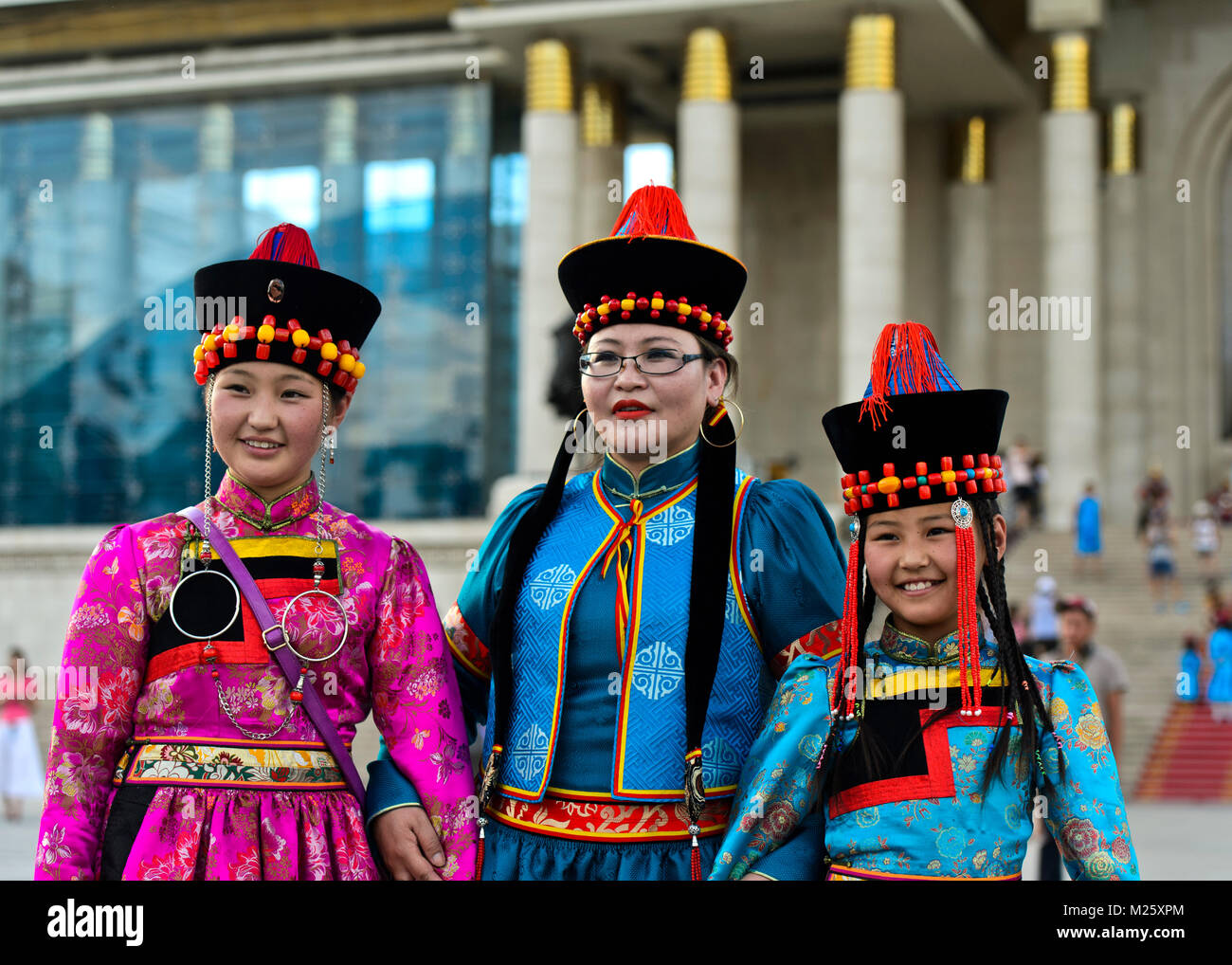 Three young women pose in traditional deel costume and the typical hat ...