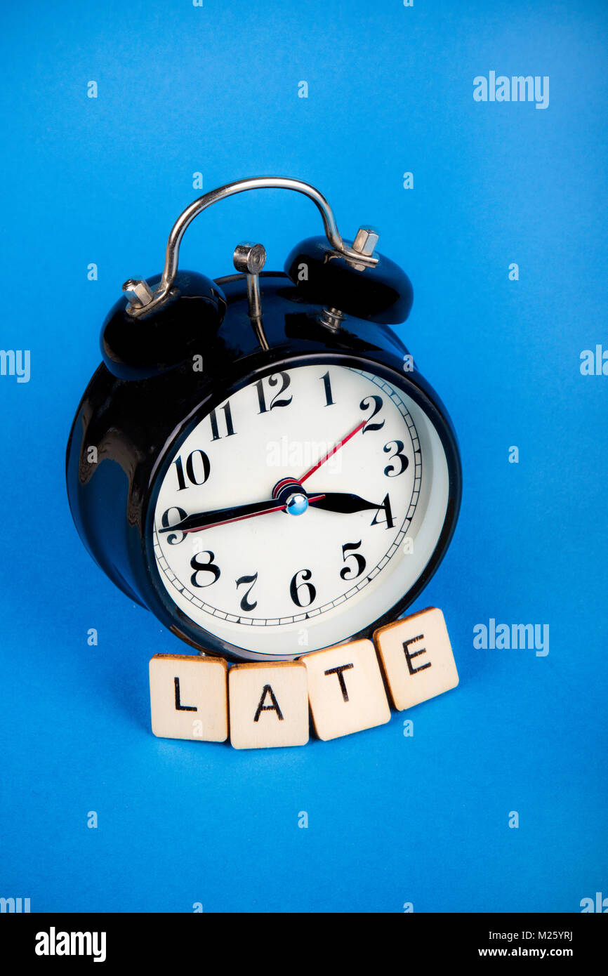 Black alarm clock with a blue background showing time with a late sign ...