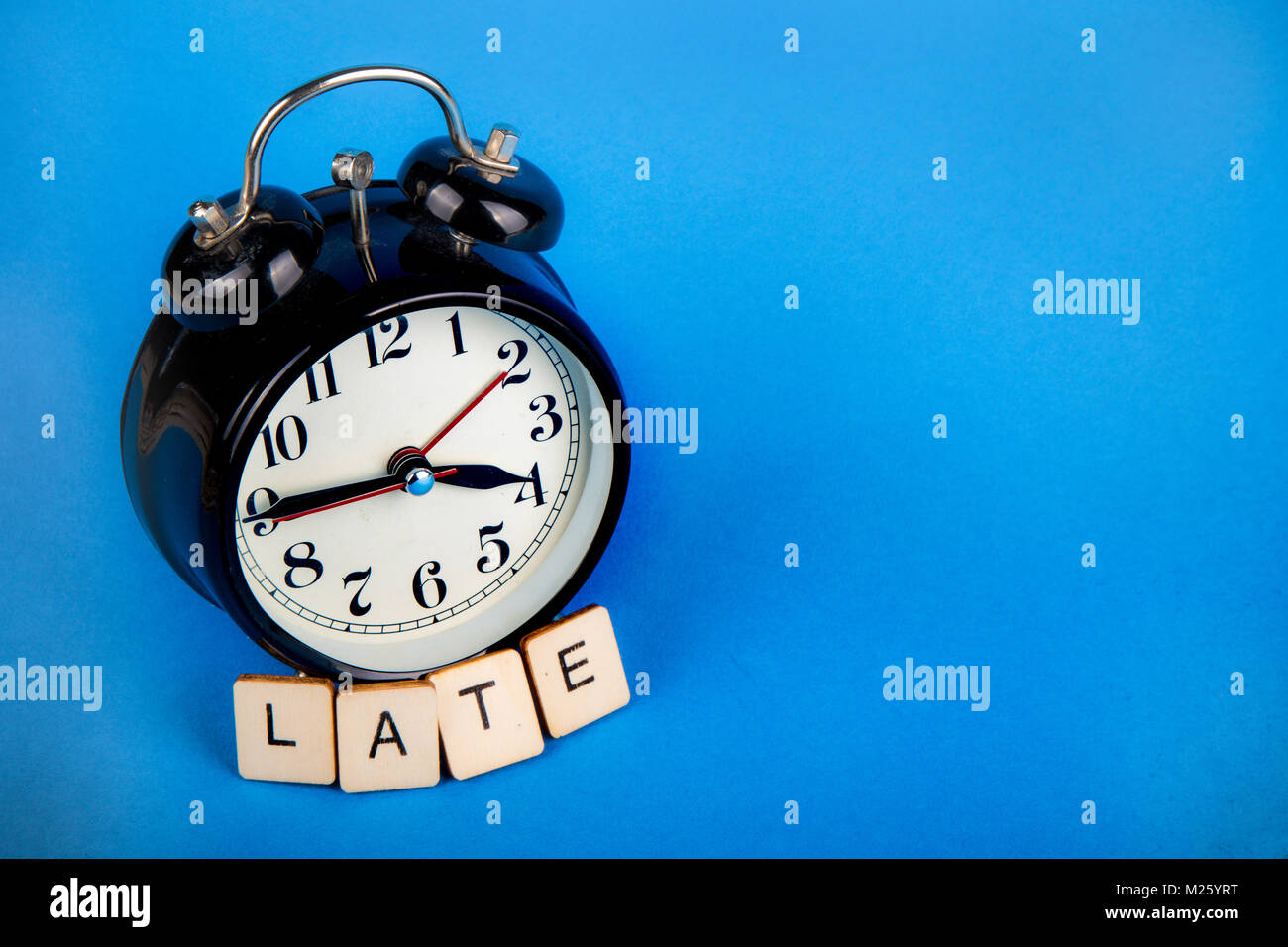 Black alarm clock with a blue background showing time with a late sign ...
