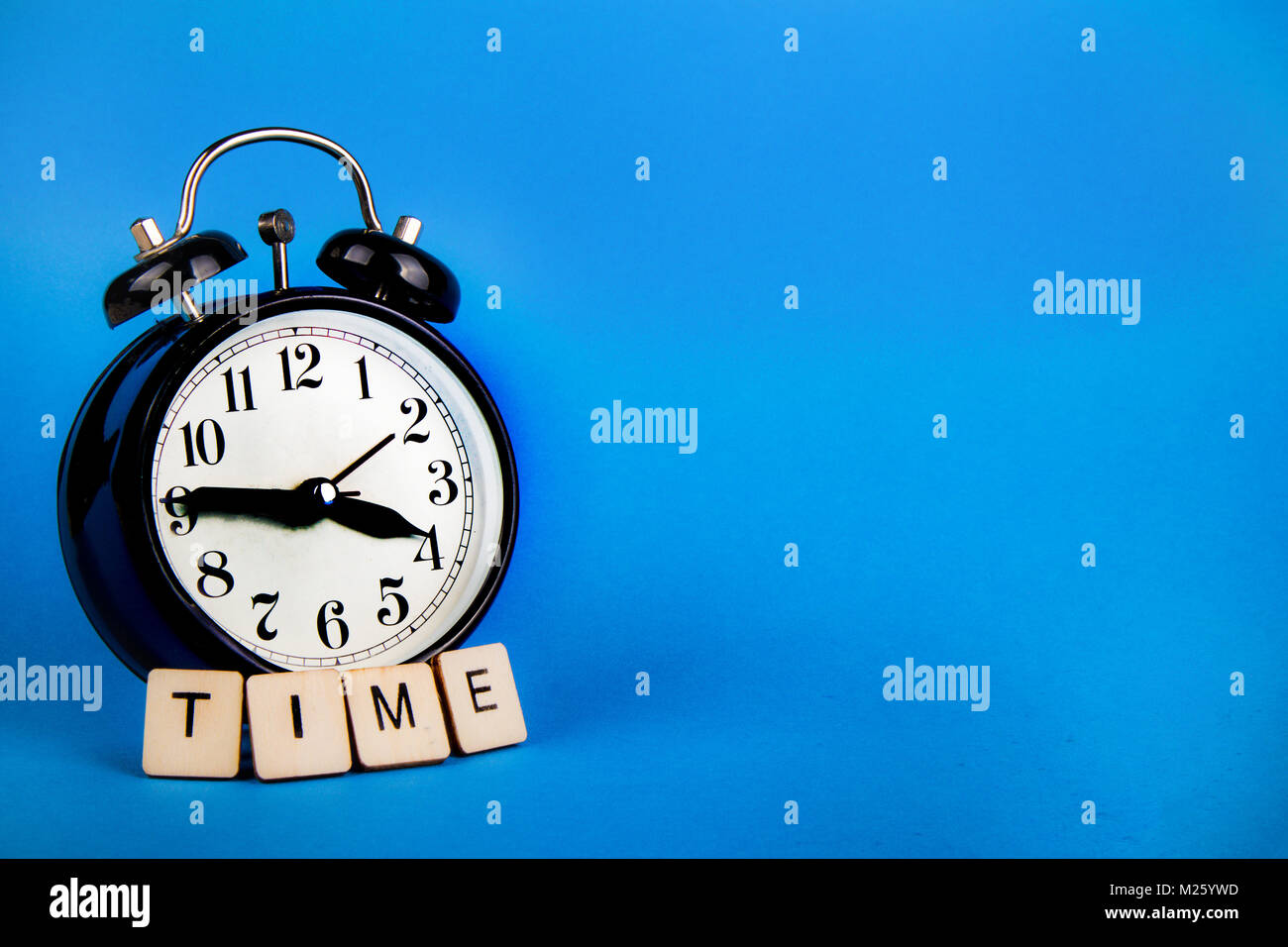 Black alarm clock with a blue background showing time and a sign saying ...