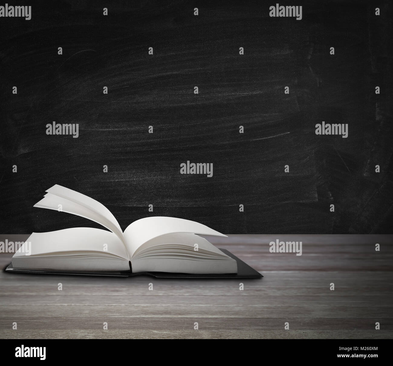 Open book on table in front of blackboard Stock Photo - Alamy