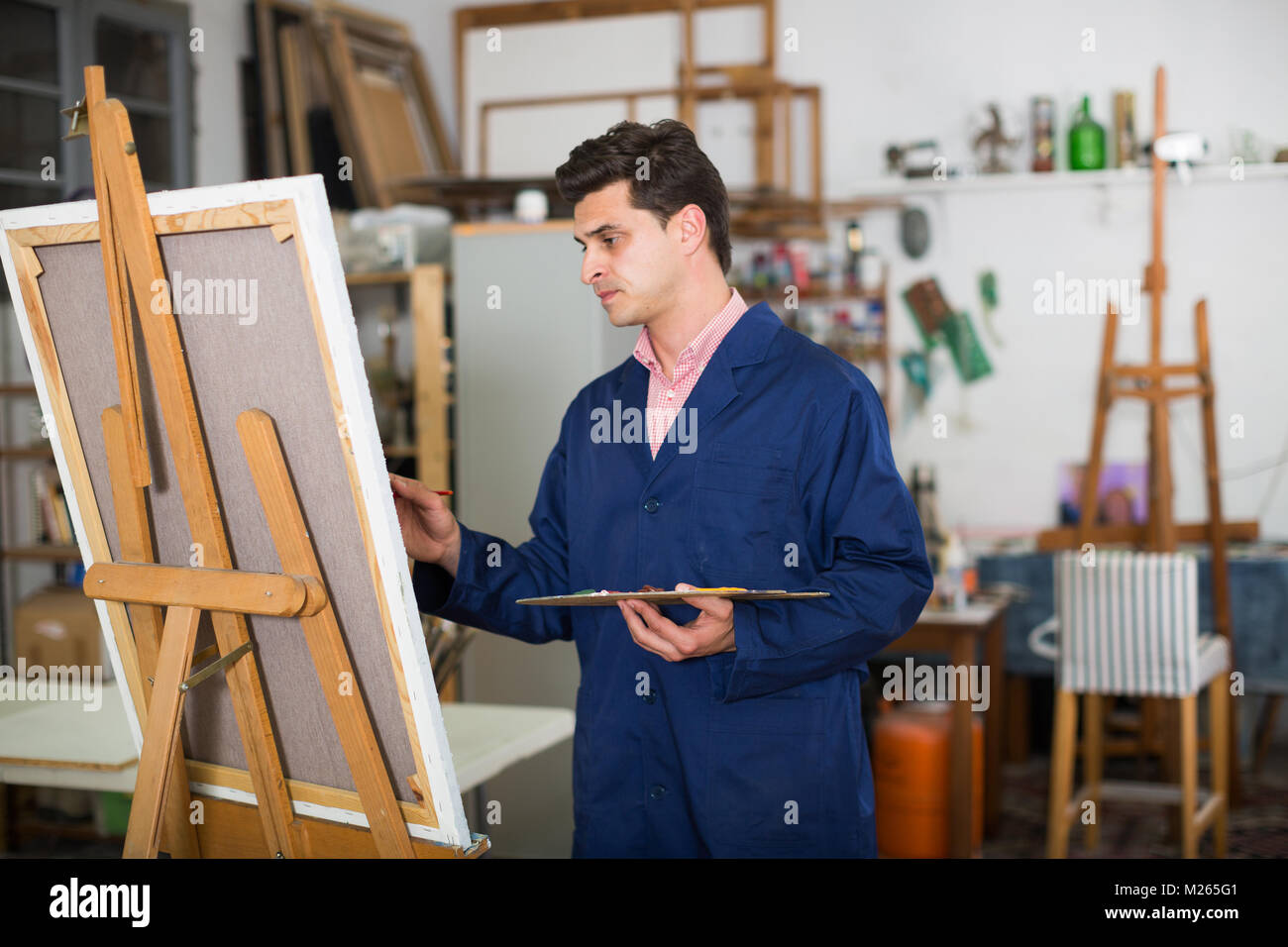Happy art painter holding artist palette and painting on canvas Stock ...
