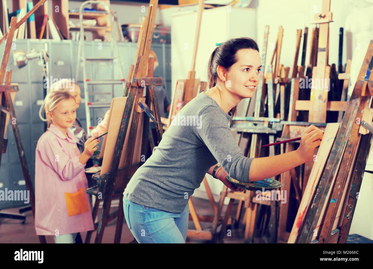 Positive woman teacher giving workshop session during painting class at ...
