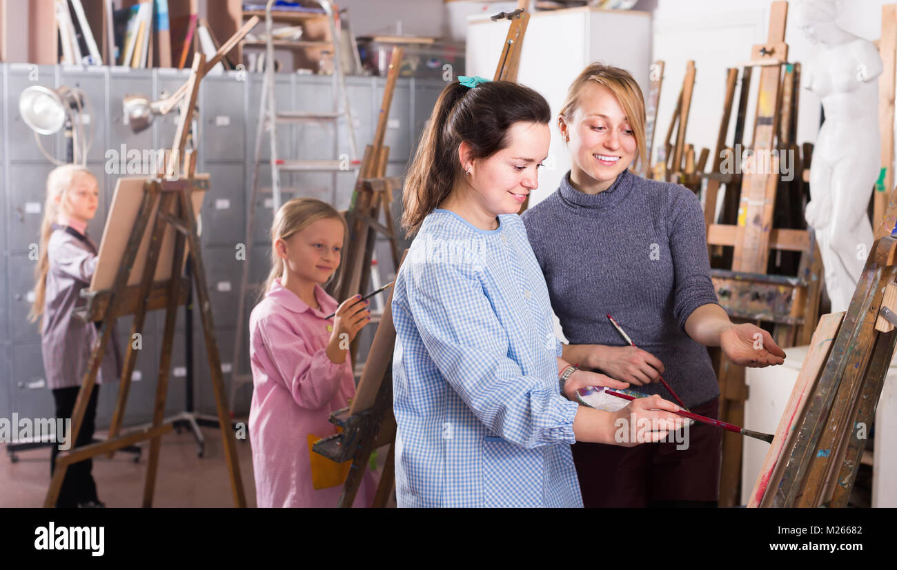 Smiling girls diligently training their painting skills drawing class ...
