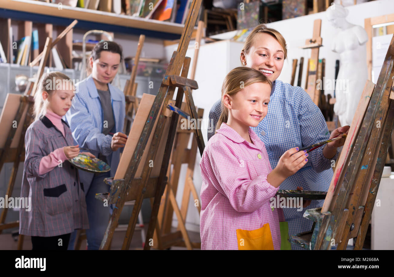 Positive female assistance girl pupil during drawing class at art ...