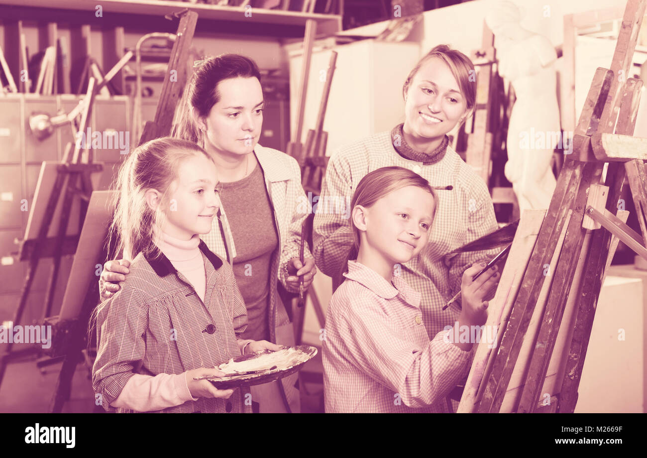 Glad female teachers helping girls during painting class at art studio ...