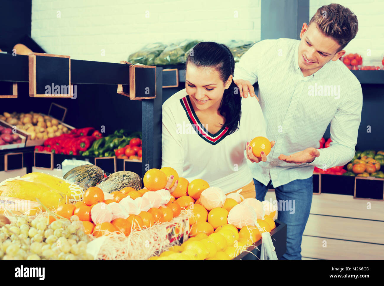 Happy loving couple deciding on fruits in grocery shop Stock Photo - Alamy