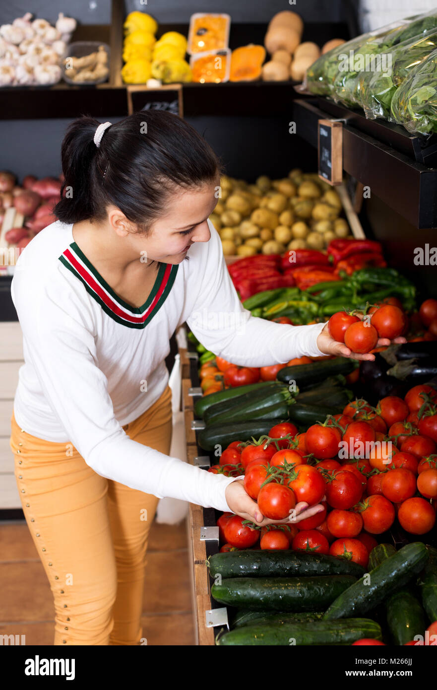 Young female customer examining various tomatoes in grocery shop Stock ...