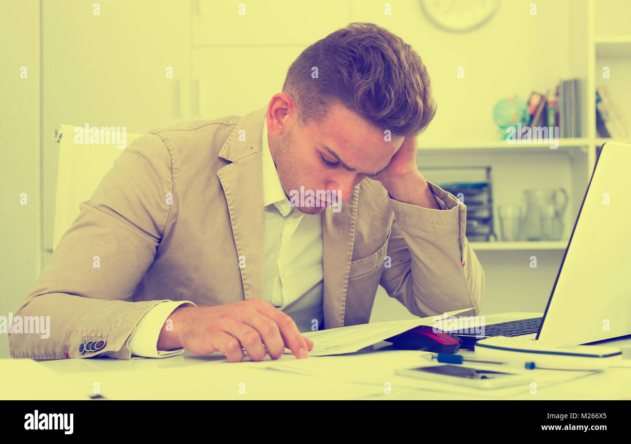 Portrait of exhausted businessman working with documents at desk Stock ...