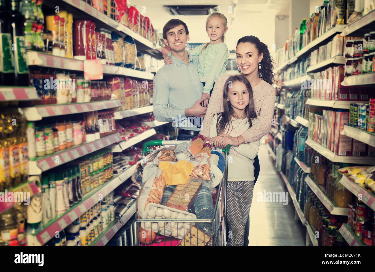 Cheerful customers with children buying food in hypermarket and smiling ...