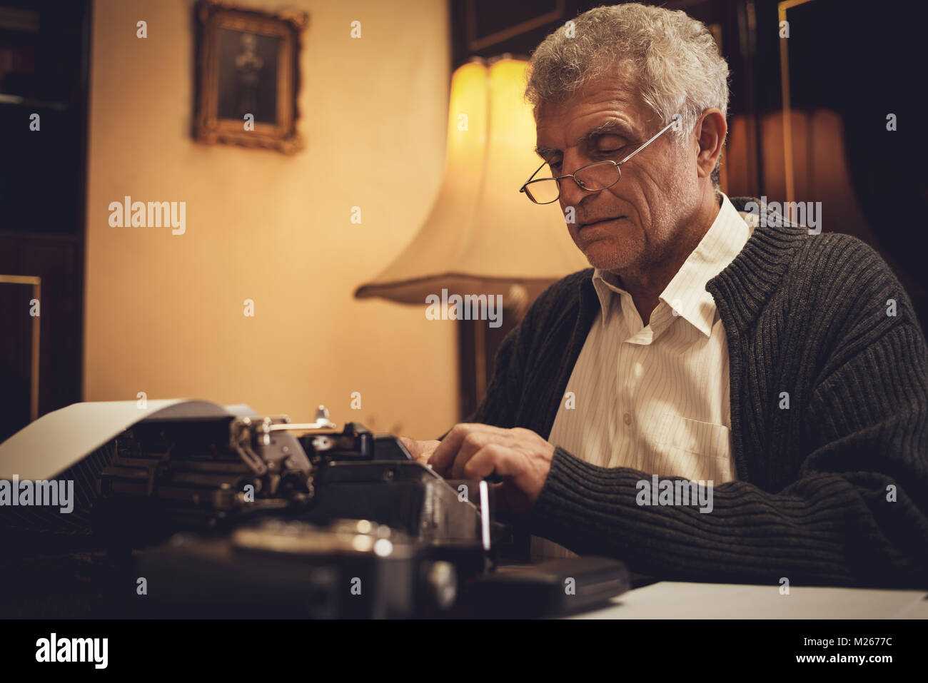 Retro Senior man writer with glasses writing on Obsolete Typewriter ...