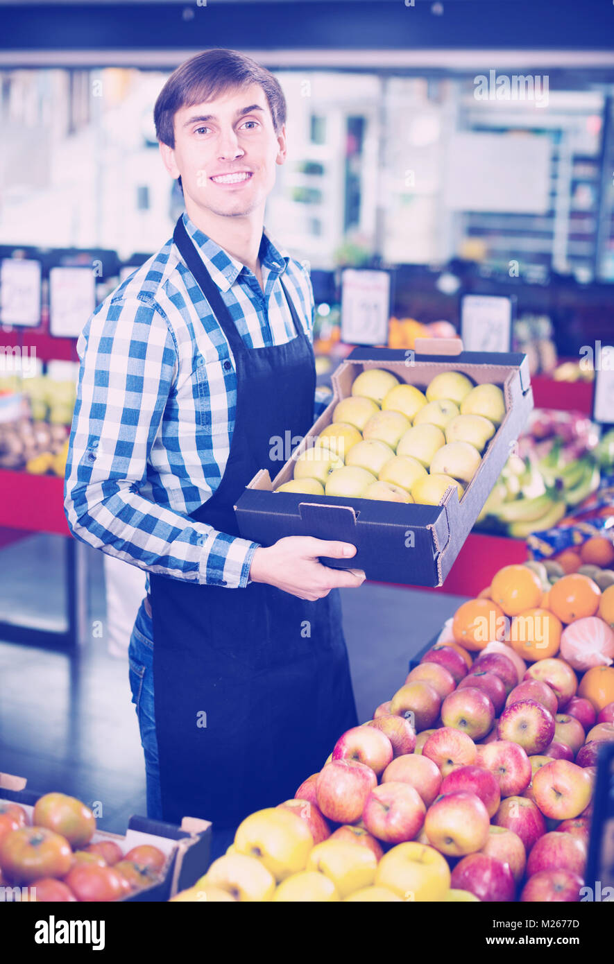 Portrait of young worker offering fruits in grocery and smiling Stock ...