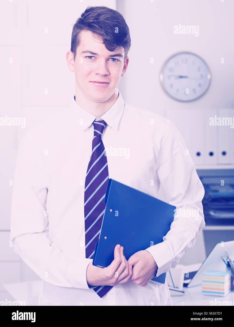 Cheerful trainee working in the office and holding documents Stock ...