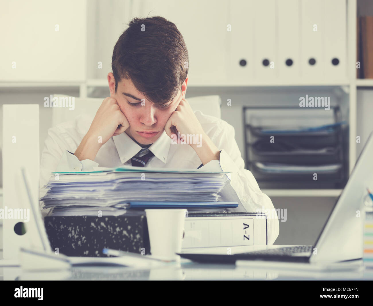 Young sad student boring near the pile of documents in office Stock ...