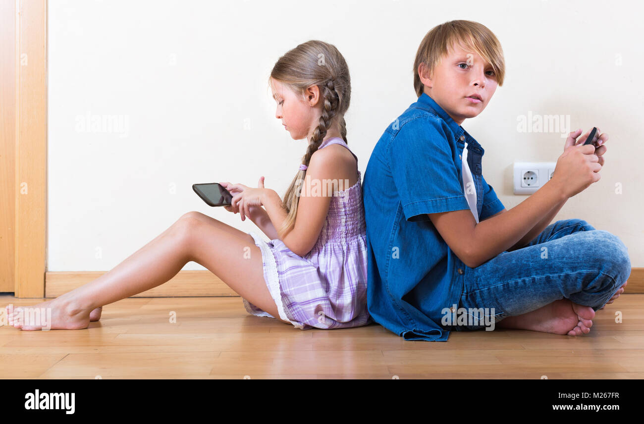 Two positive kids playing with smartphones in domestic interior Stock ...