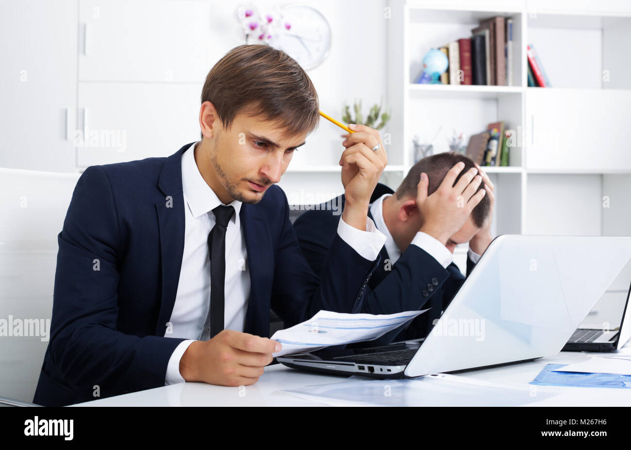 Two serious annoyed business male assistants making mistake in company ...