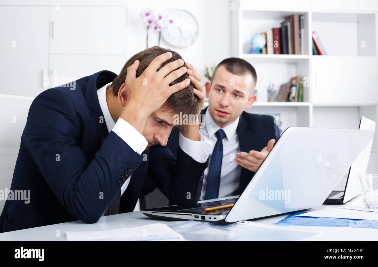 Two young annoyed business male assistants making mistake in company ...