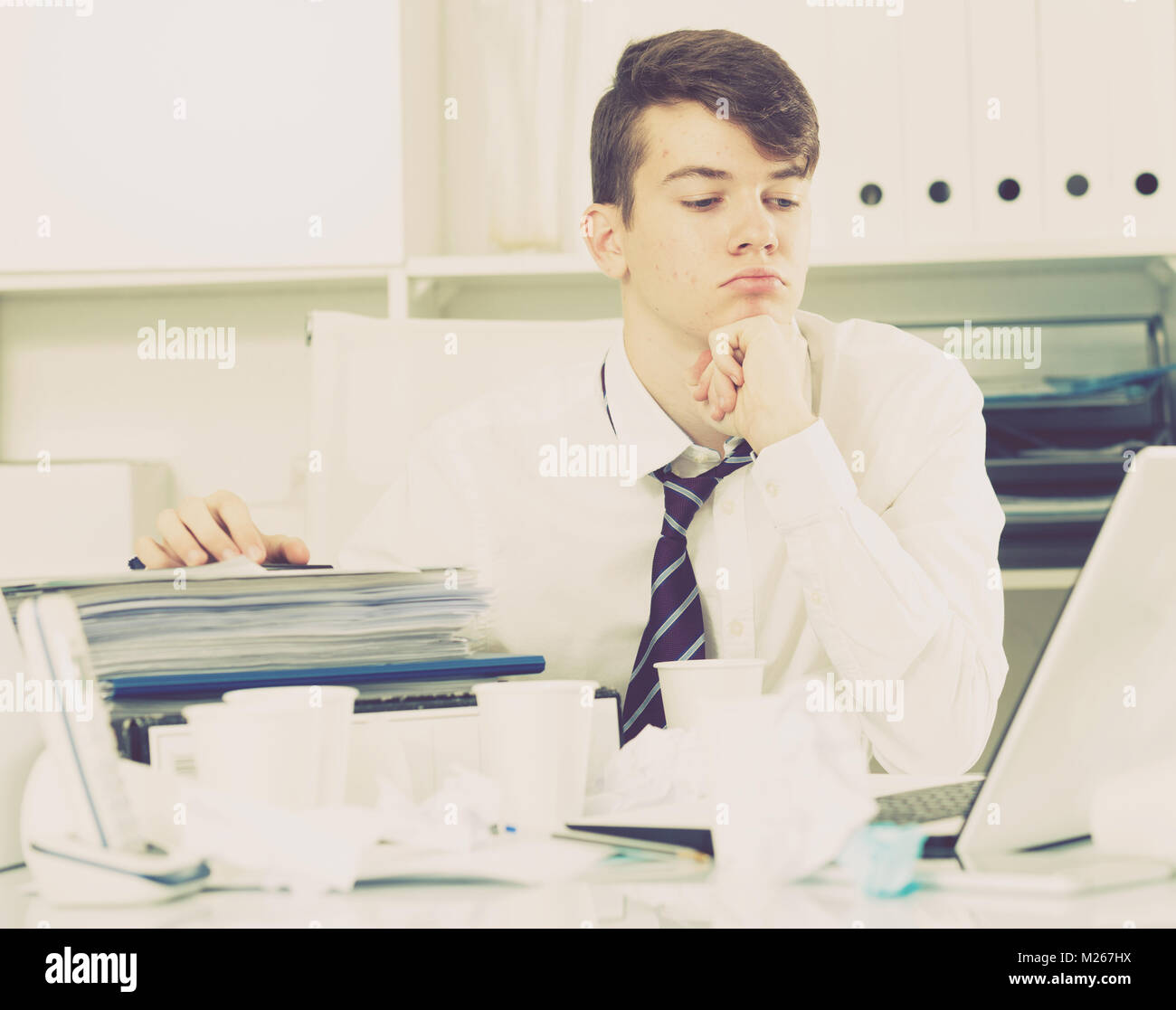 Young sad student boring near the pile of documents in office Stock ...