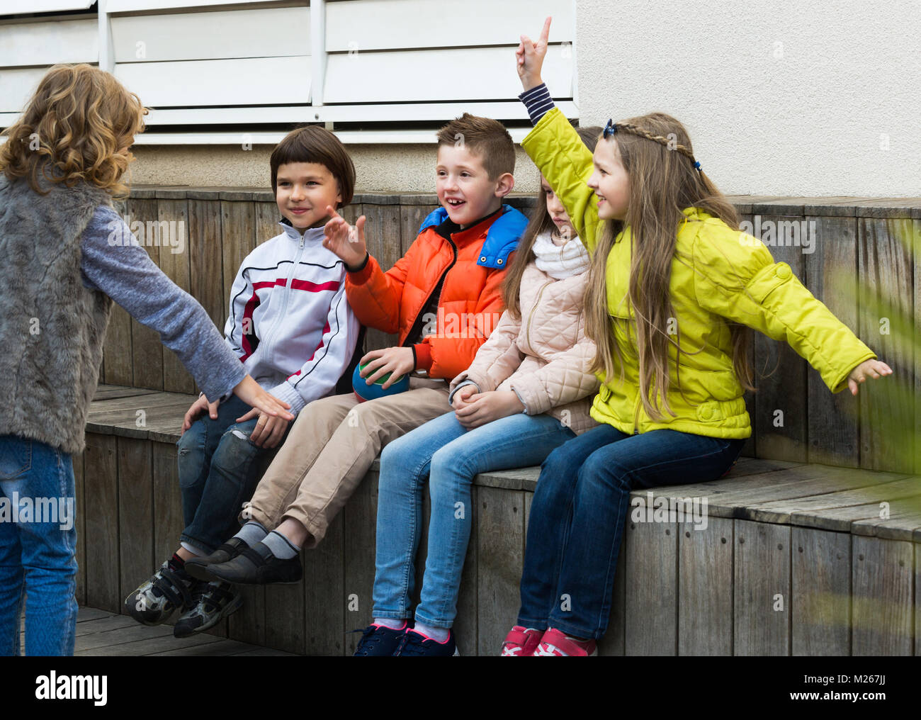 Group of children sitting on bench and playing charades together Stock ...