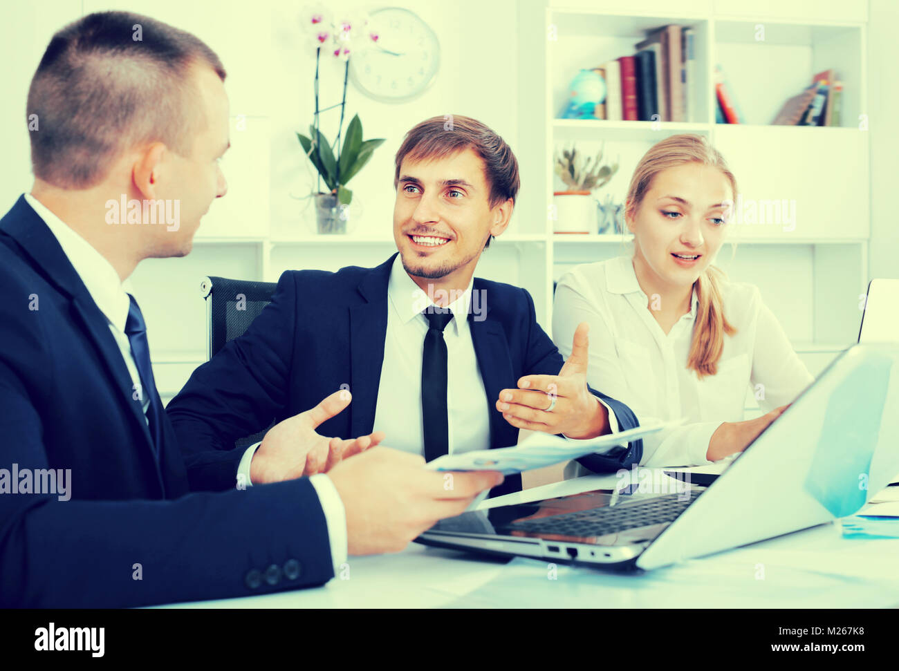 Three business male and female assistants in formalwear having a ...