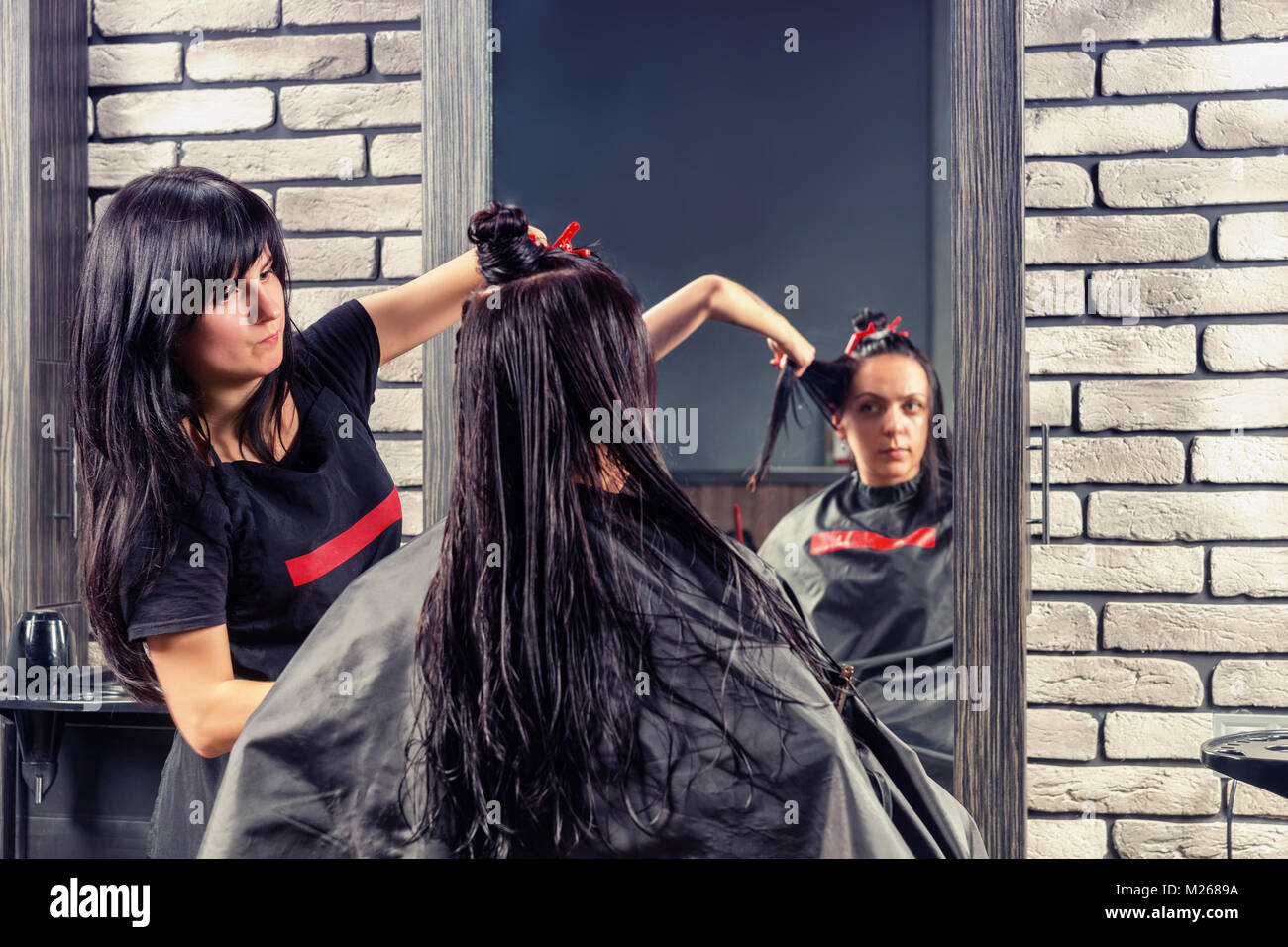 Attractive female hairdresser cutting and modeling brown hair by ...