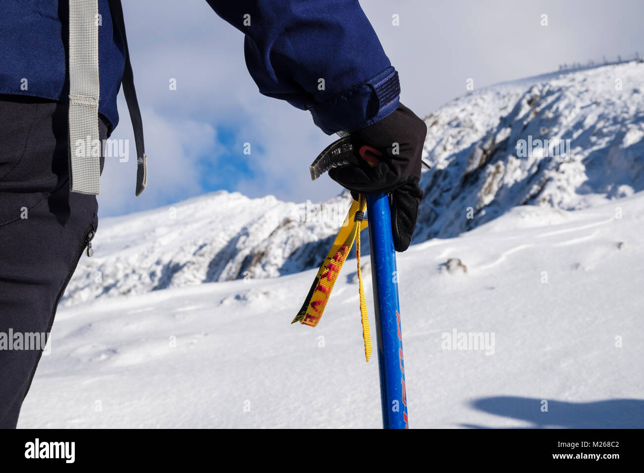 Hiker holding an ice axe in hand hiking on Rhyd Ddu path at Llechog ...