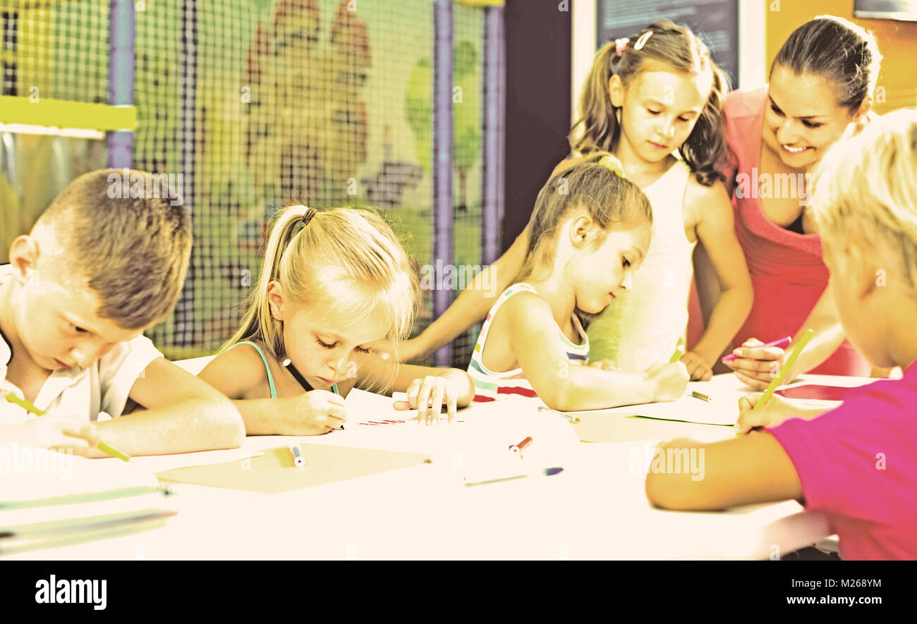 Diligent kids drawing together with tutor at hobby group indoors Stock ...