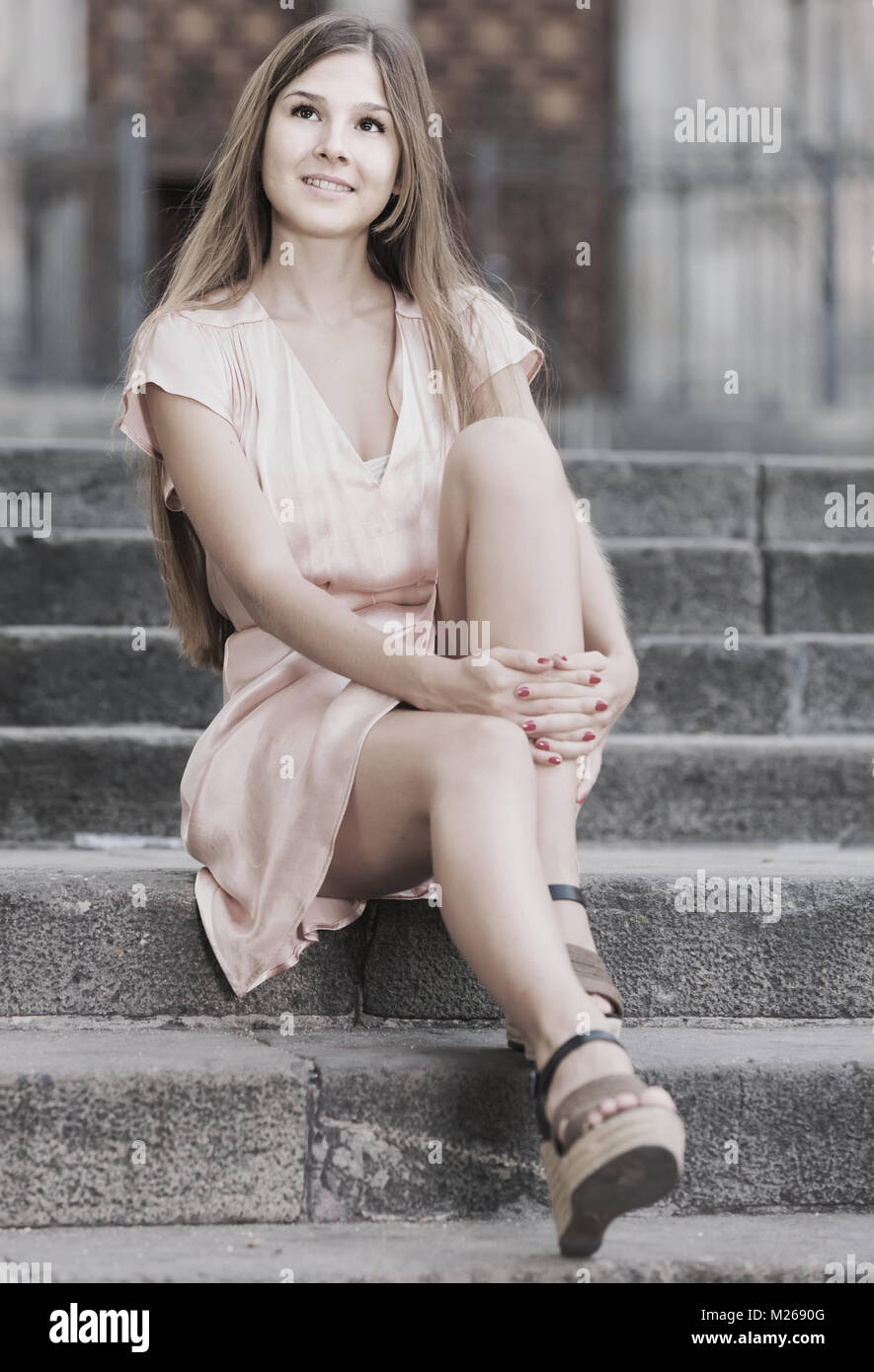 young smiling belgian female in rose dress sitting in city Stock Photo ...