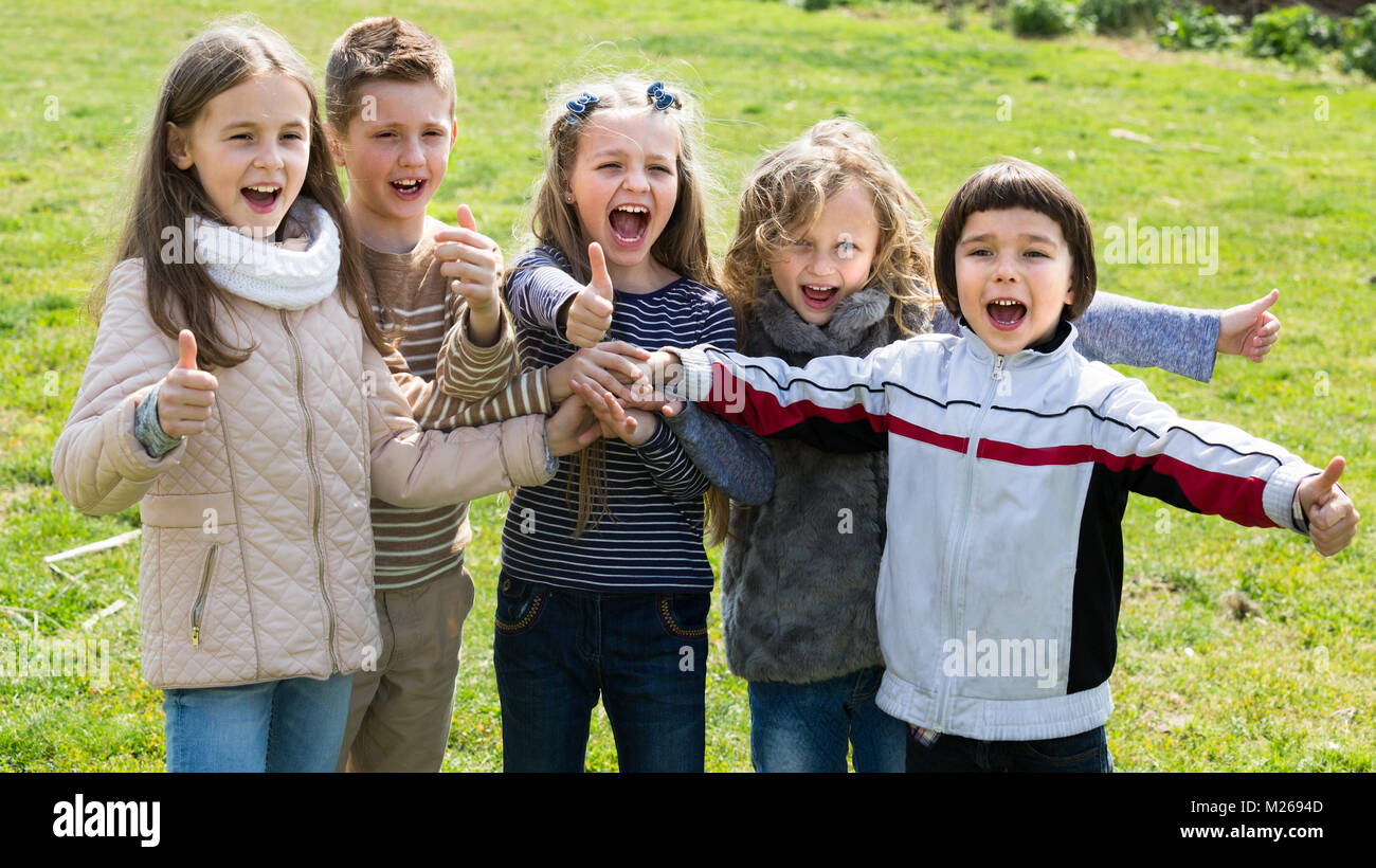 Happy kids having fun and showing thumbs up outdoors Stock Photo - Alamy